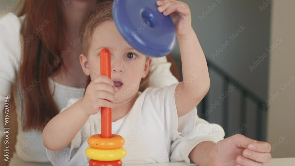 the child collects a toy pyramid. mom plays with son at home happy ...