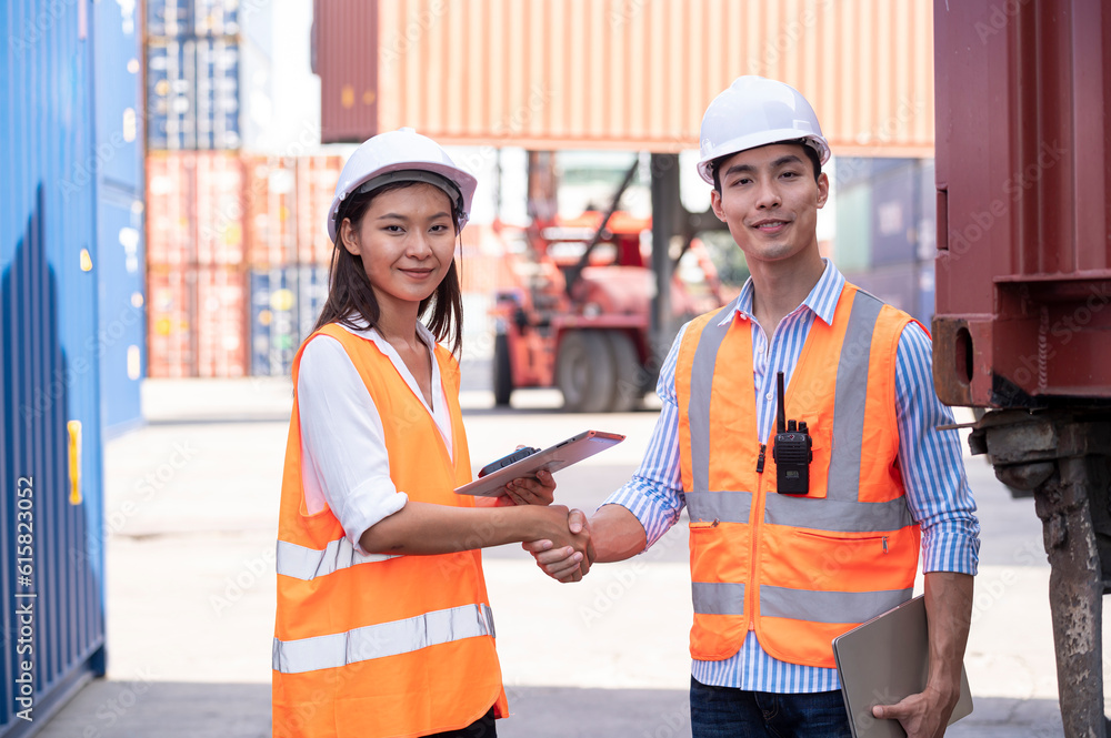 Asian dock control man and woman logistics worker wear safety helmets ...