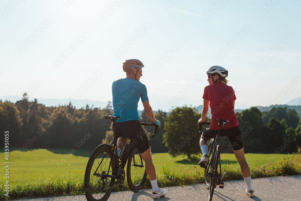 Professional Caucasian racing cyclists couple riding on an asphalt road ...
