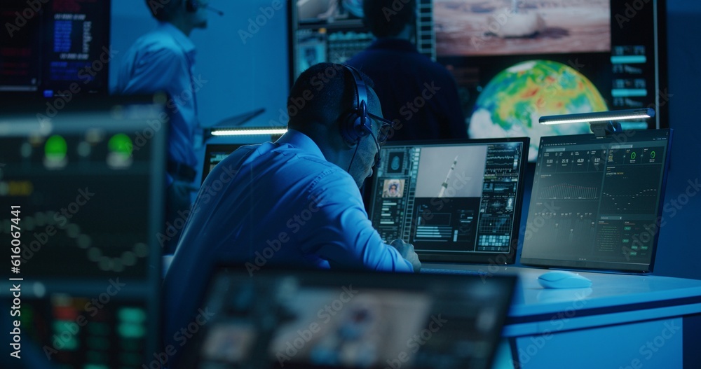 African American flight control employee monitors space mission on ...