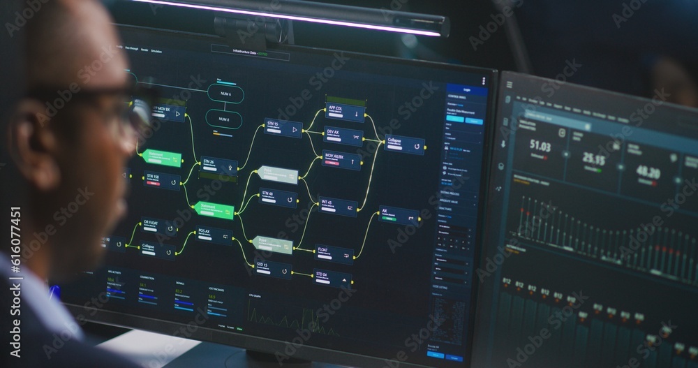 African American software engineer looks at computer screen with displayed big data server and ...