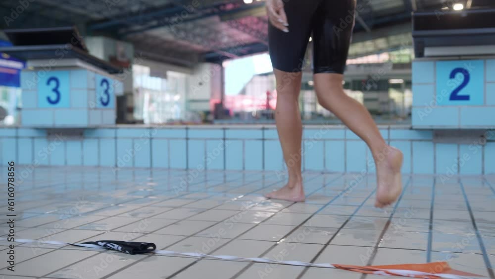 Female swimmer approaching a diving board, taking a start position and ...