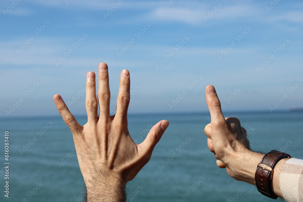 Hand doing,showing number six gesture symbol on blue summer sky nature ...