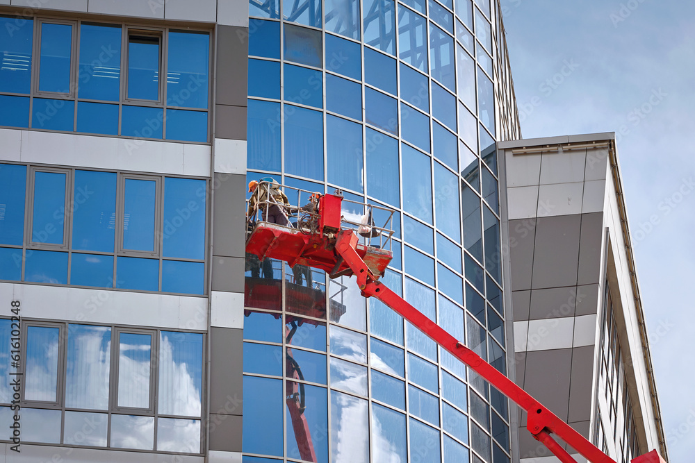 Foto de Man on crane bucket washing glass facade. Window cleaner ...