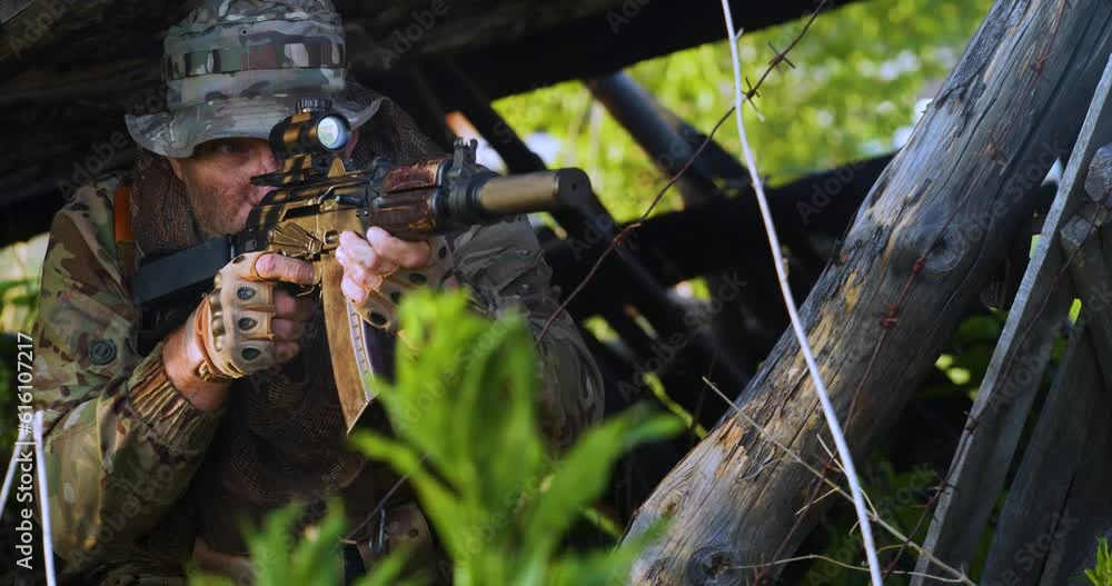 Close-up video of a mercenary soldier fires an automatic rifle from ...