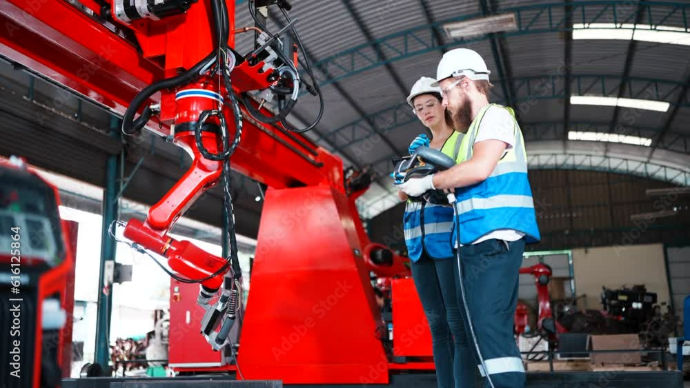 Technician programs a robot arm with a digital tablet and assembly ...
