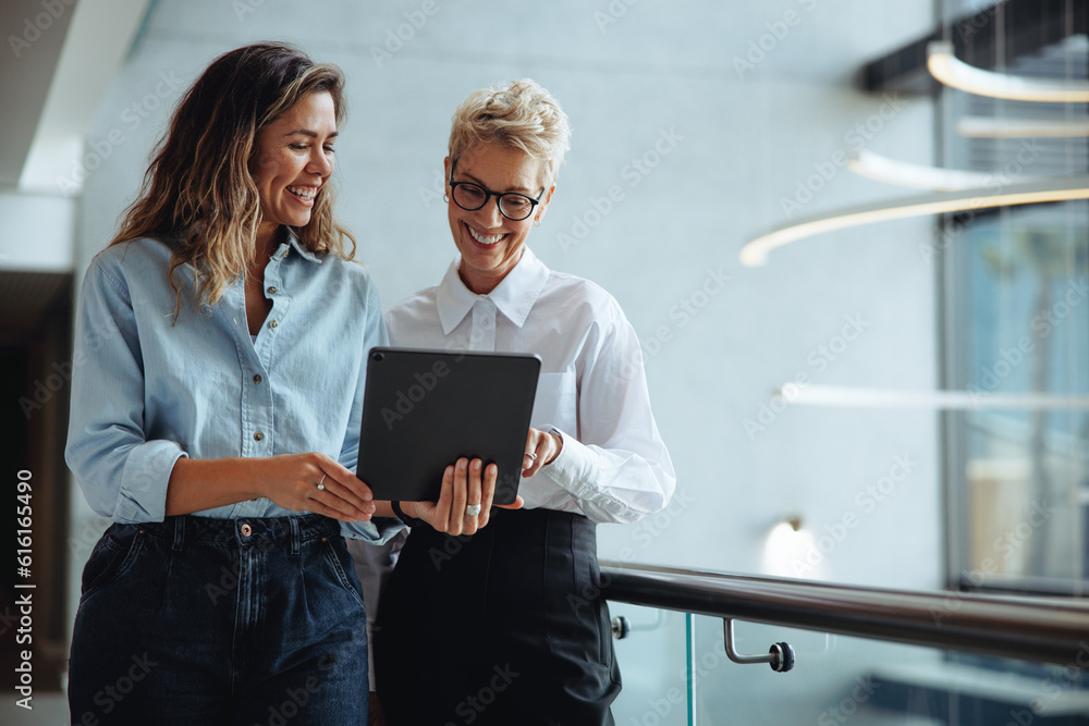 Female executive assistant using a tablet to show her boss a positive ...