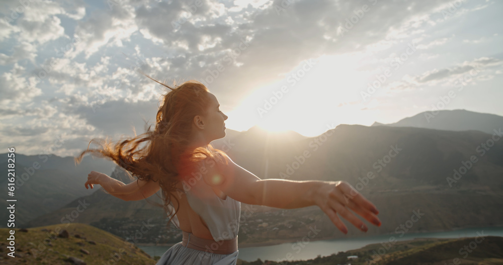 Woman in white dress standing on top of a mountain with raised hands ...