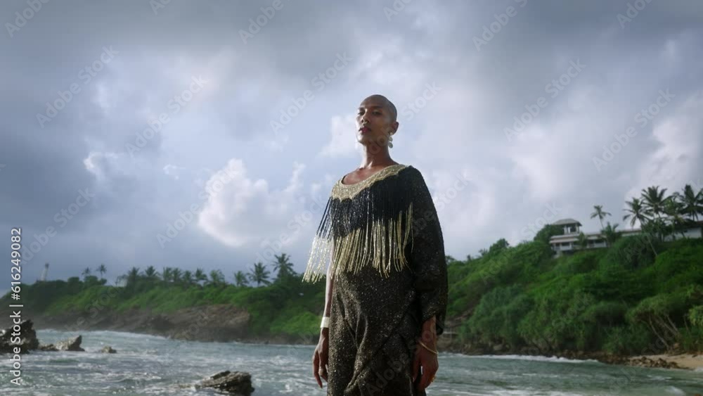 Gender fluid person of color in luxury clothes, jewelry walks on scenic ...