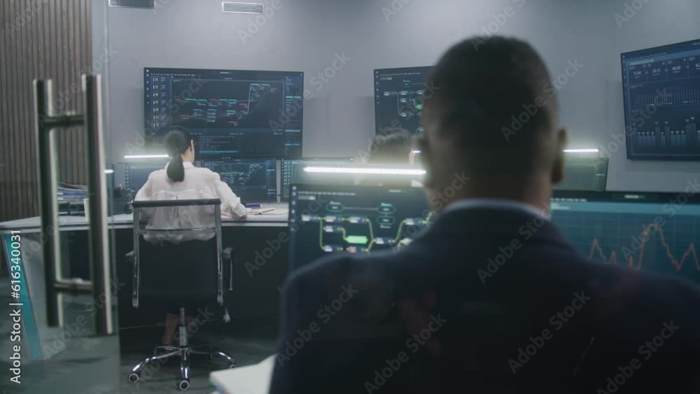 African American IT engineer works at computer with displayed real-time ...