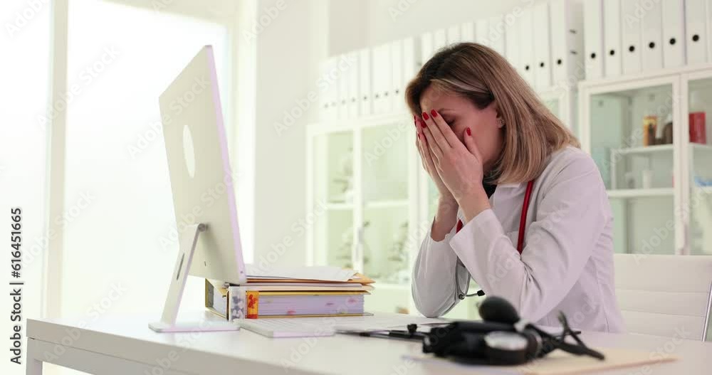 Frustrated nurse works on computer in clinic. Unhappy crazy female ...