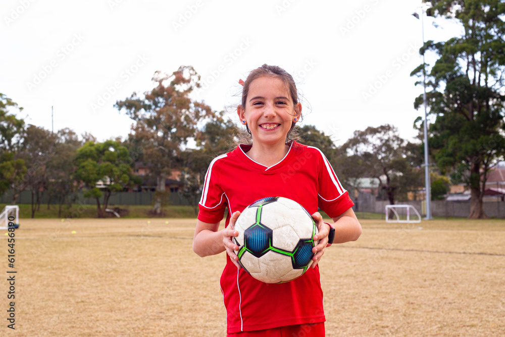 Tween girl in a red soccer uniform holding a ball Stock Photo | Adobe Stock