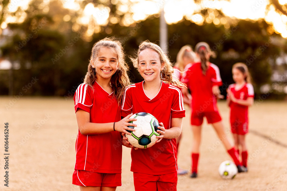 Two tween football players standing together at a sports oval holding a ...