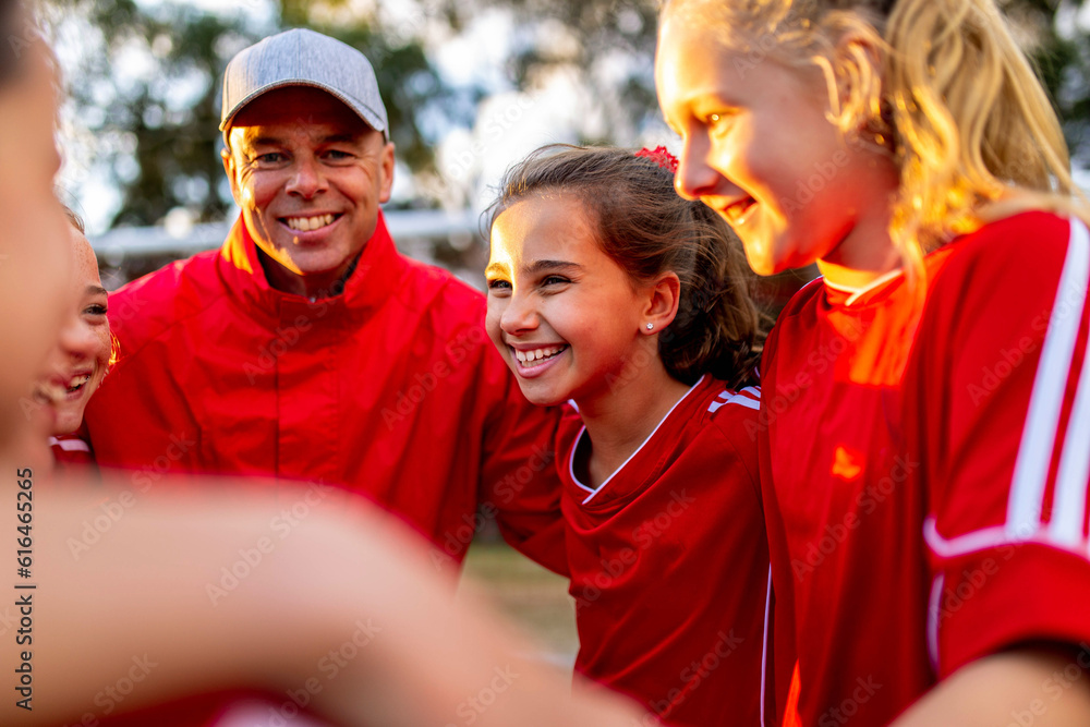 Close-up of female tween football team players in a huddle preparing ...