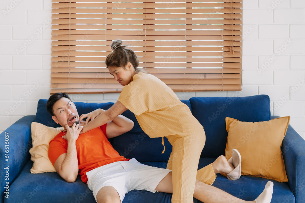 Funny asian husband and wife fighting on the sofa in the house. Stock ...
