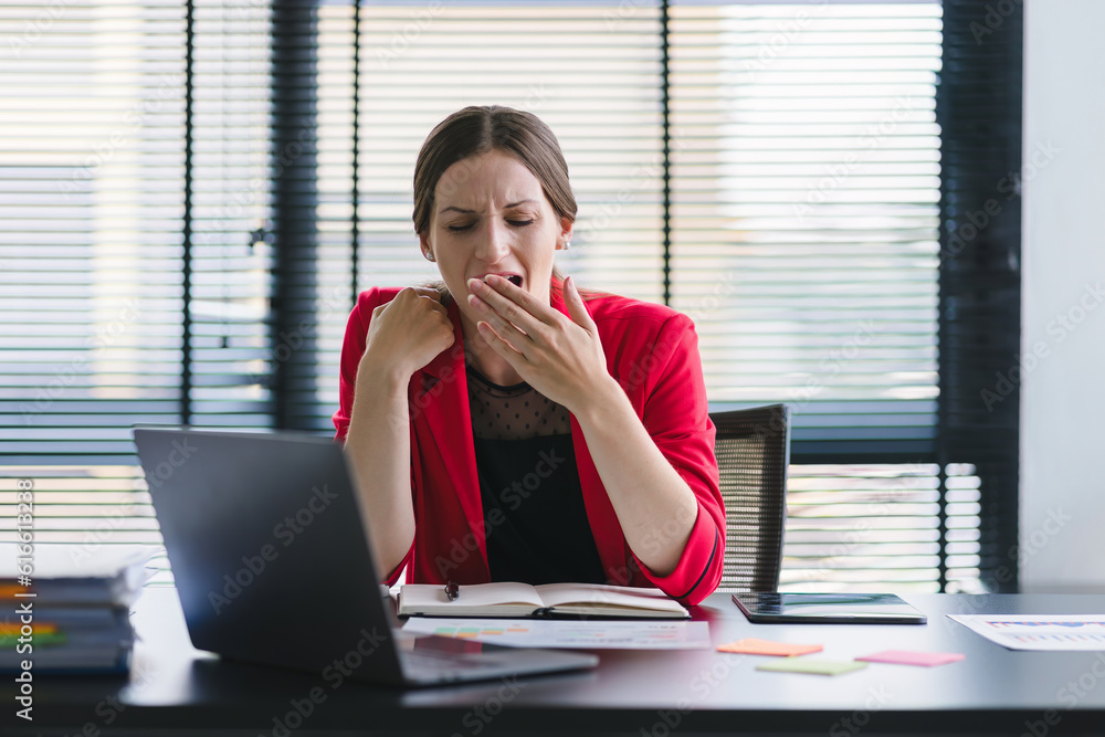 The stressed and exhausted millennial businesswoman is seen sitting at ...