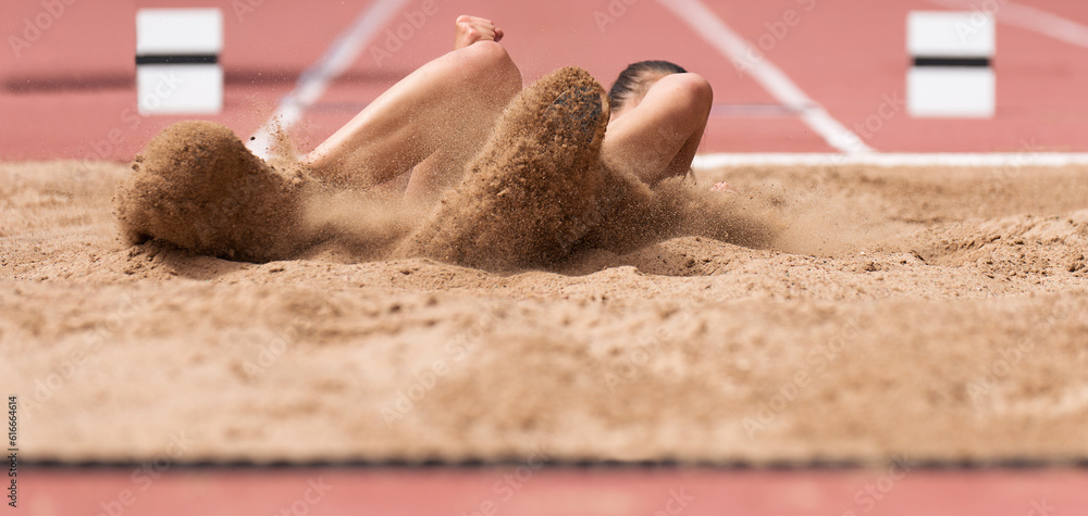 Female athlete long jump landing sand spray, landing in long jump in ...
