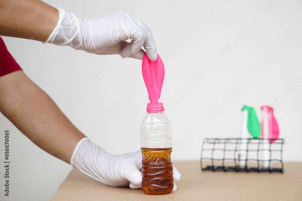 Foto de Close up hands doing science experiment with pink balloon, Mix ...