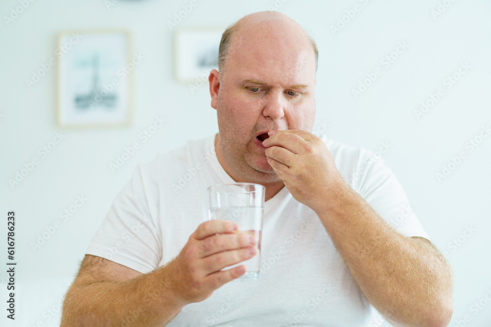 Unwell caucasian man got a sickness, oversize fat man taking a pills ...