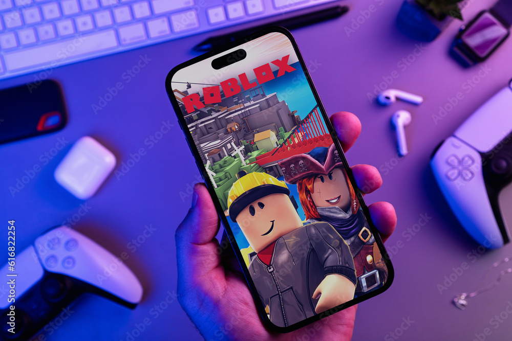 Man holding an iPhone 14 Pro smartphone with Roblox game app with PS5 ...