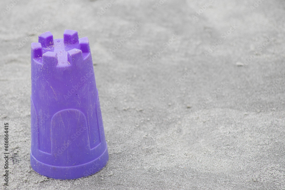 abandoned purple bucket on the sand at the beach, not being played with ...