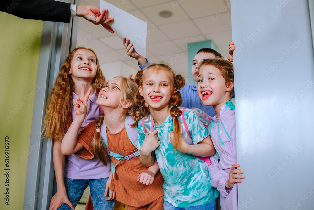 Hand of teacher giving report card to school children standing in ...