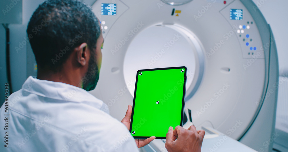 African American doctor is looking at chroma key screen of tablet ...