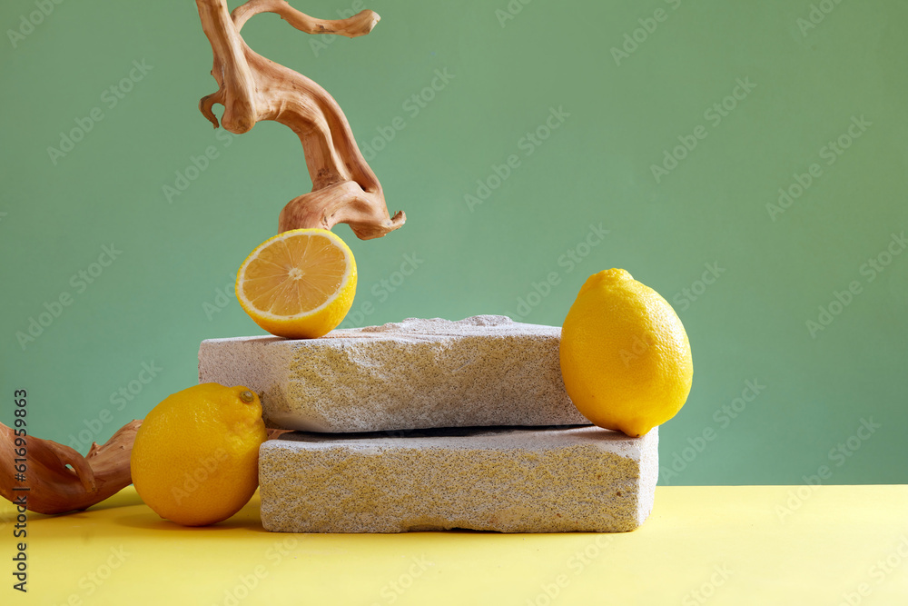 Front view of block of stone, fresh lemons and dry twigs decorated on ...