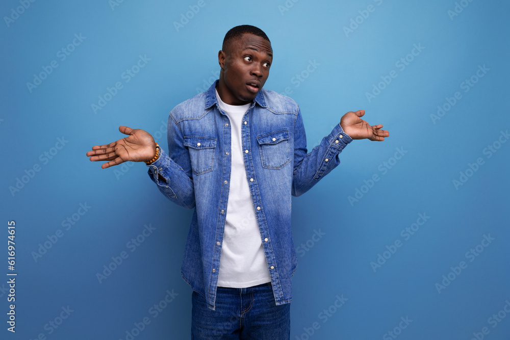 handsome young american man in denim jacket shrugging on blue ...