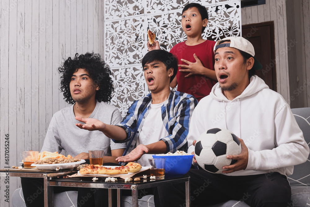Shocked friends watching football game sitting on the sofa with open ...