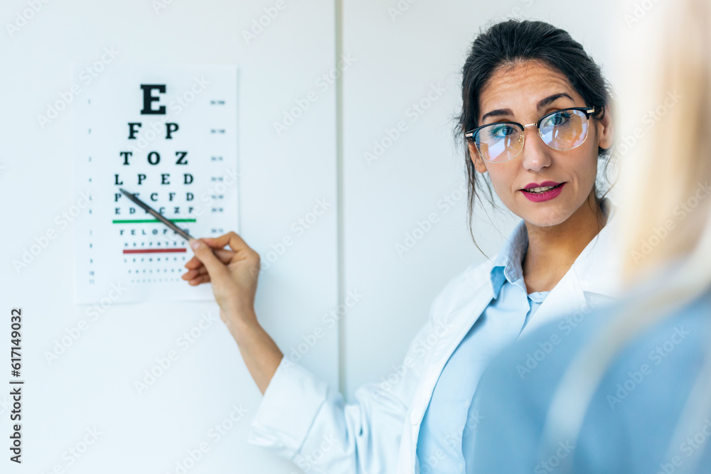 Beautiful female optician doing eye test with eye chart on her patient ...
