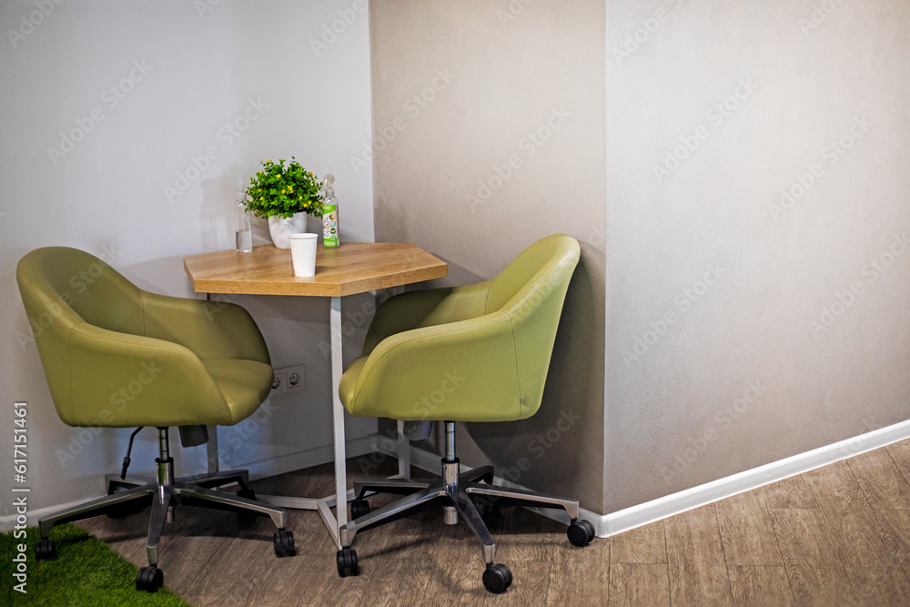 table with green office chairs in the corner of a concrete wall in a ...