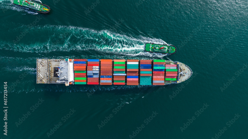 Aerial top view of cargo ship carrying container and running with tug ...