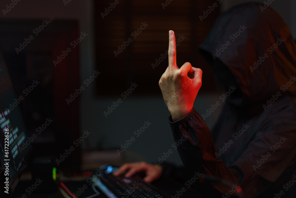Hacker in hoodie showing middle finger and typing code to hacking ...