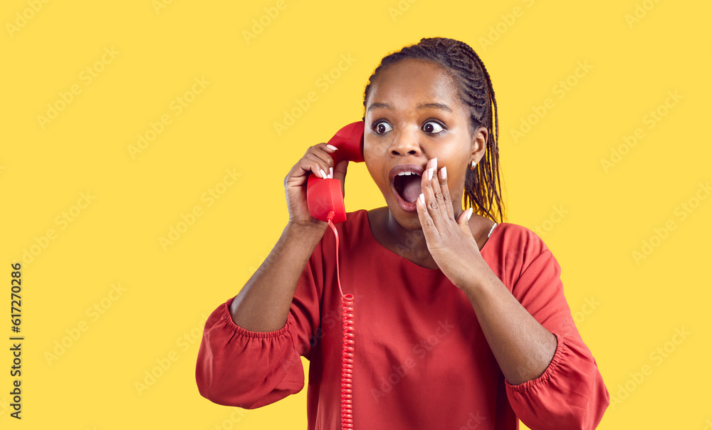 Funny amazed dark-skinned young woman talking on landline phone ...