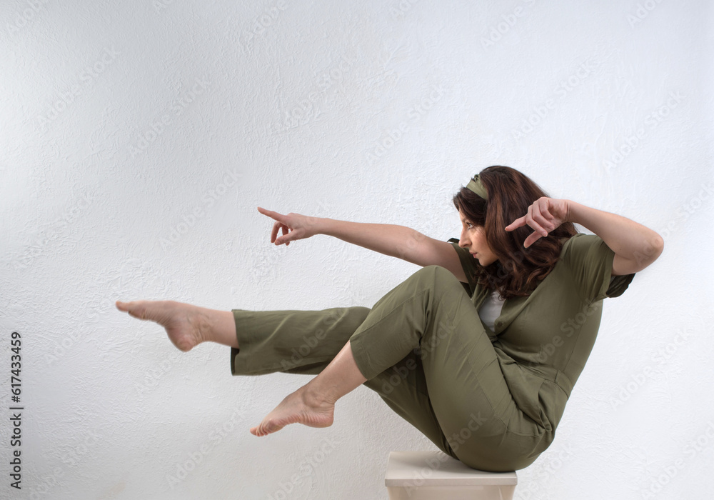 The girl sits in a falling balancing pose on a white background and ...