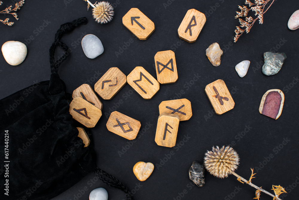 Black textile bag with stack of wooden runes and stones on a table ...