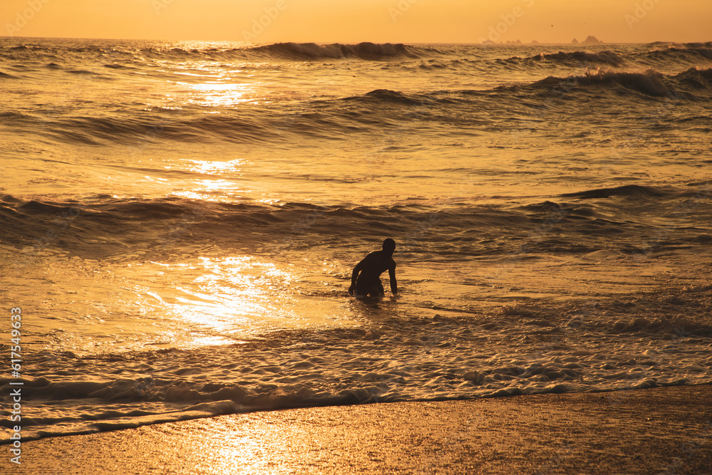 Personas a contraluz disfrutando de las olas del mar en la hora dorada ...