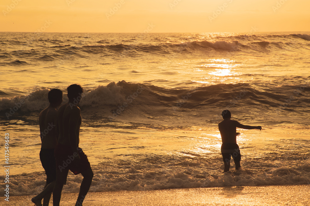 Foto de Personas a contraluz disfrutando de las olas del mar en la hora ...