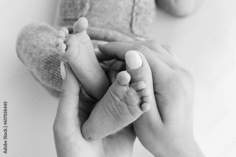The palms of the father, the mother are holding the foot of the newborn ...