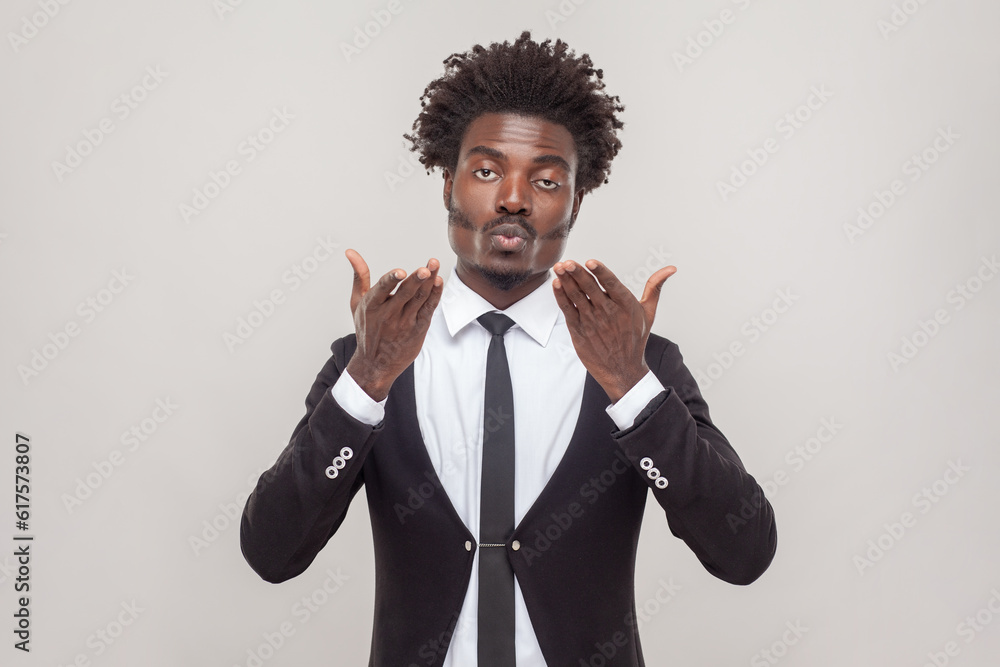 Portrait of pleased man with Afro hairstyle stretches hands near face ...