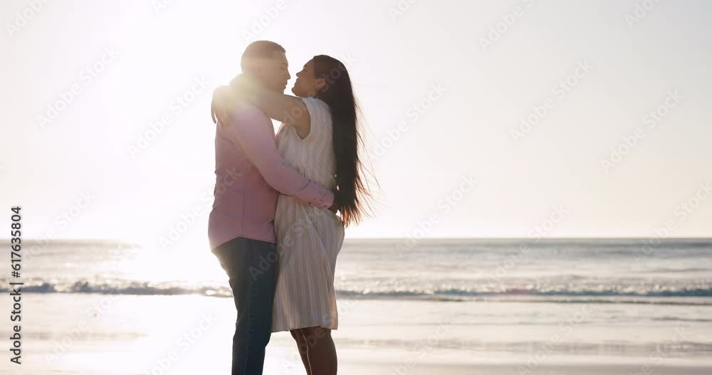 Beach, hug and couple kiss at sunset at the ocean for travel, fun and vacation in nature. Love ...
