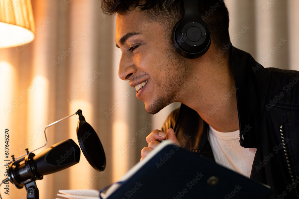 Happy biracial transgender man in headphones, making notes and talking ...