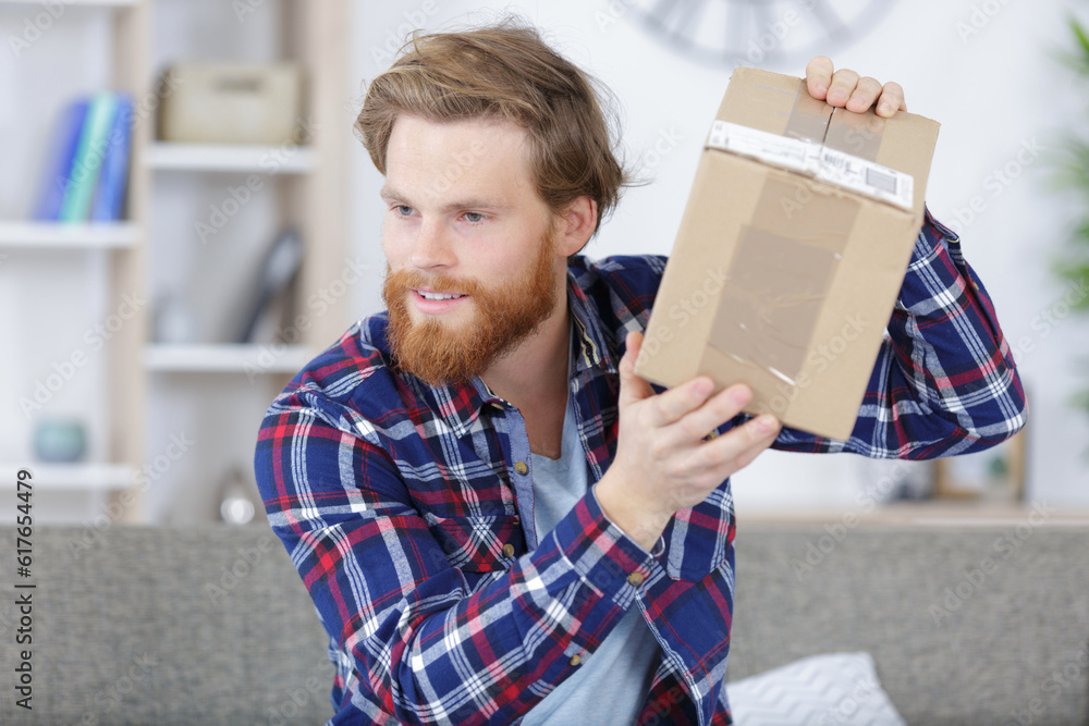 guy shaking cardboard box to guess its contents Stock Photo | Adobe Stock