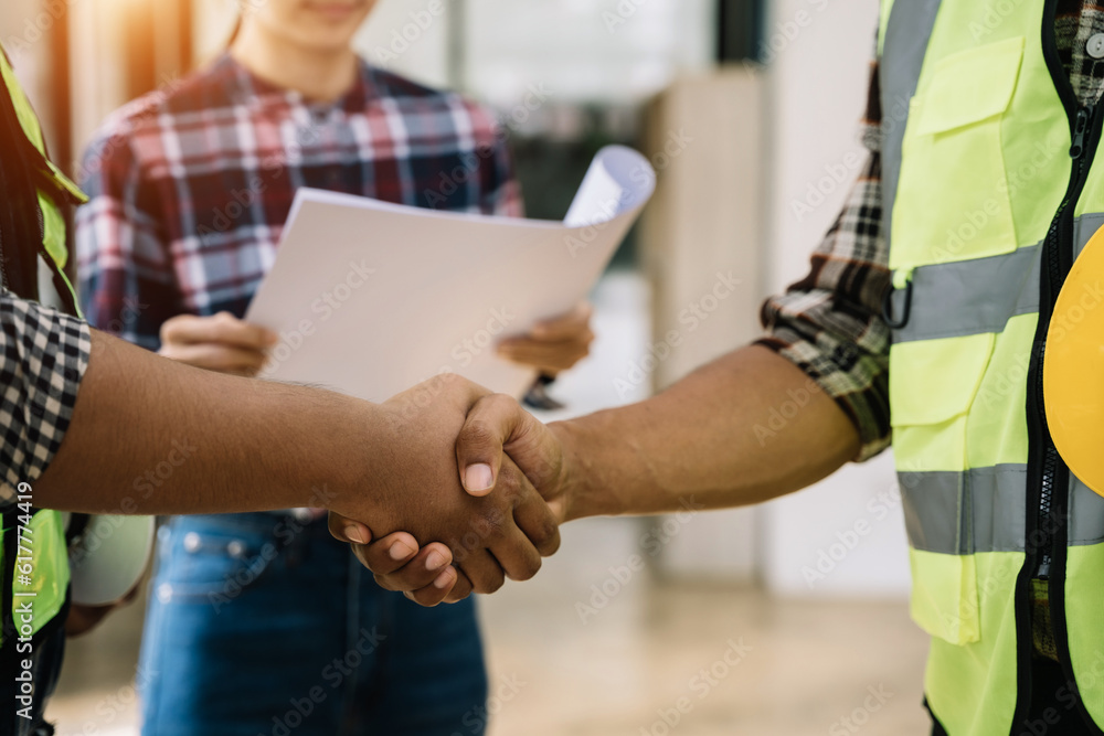 Construction workers, architects and engineers shake hands while ...