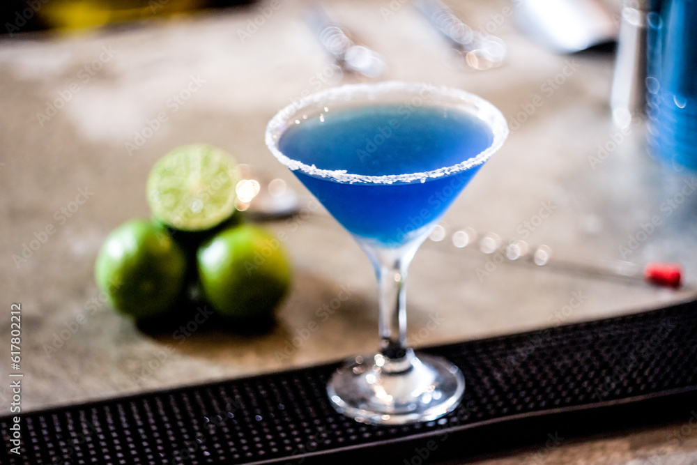 Summer alcohol fresh fruit drink. Blue colored cocktail with lemon on ...
