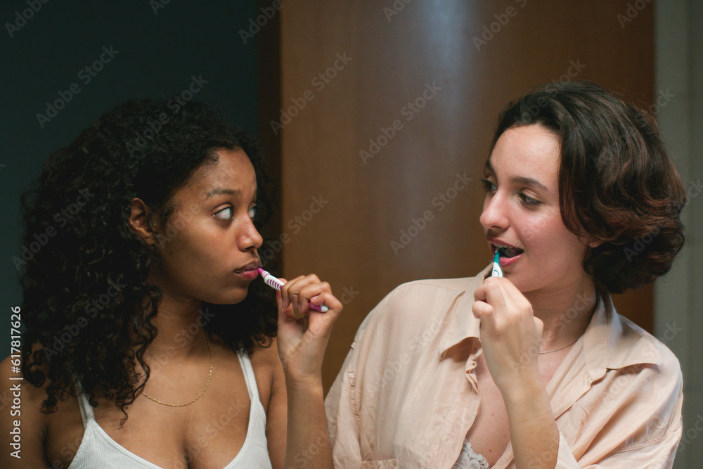 Young diverse women standing and brushing teeth together Stock Photo ...