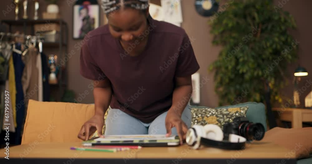 African woman settles on couch takes out computer, diving into work as ...