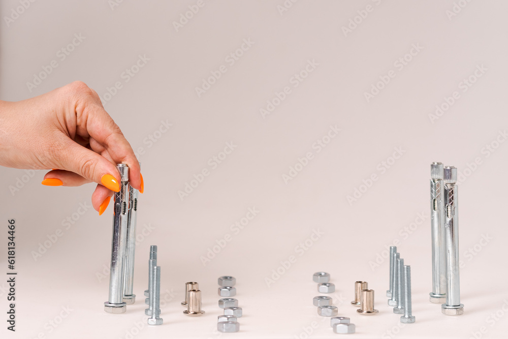 screws and nuts and bolts, stand on a light background, the hand moves ...