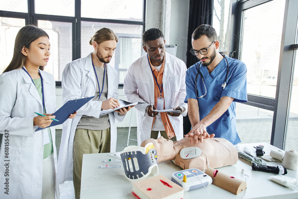 medical instructor showing chest compressions on CPR manikin near ...